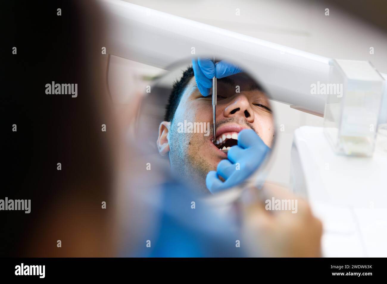 A patient examines his smile in a mirror during a dental checkup ...