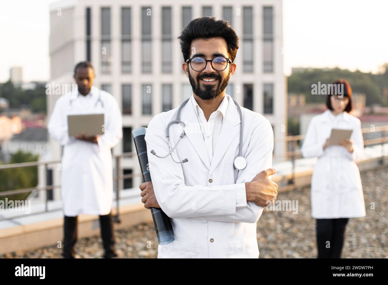 Male doctor in white lab coat posing on camera with crossed hands and ...