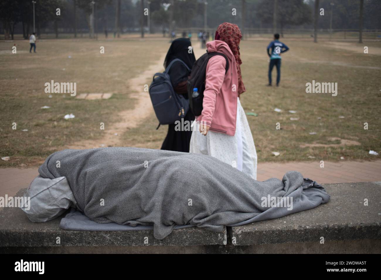 Dhaka, Bangladesh. 22nd Jan, 2024. A street man covers himself with a blanket in Sohrawardy ...
