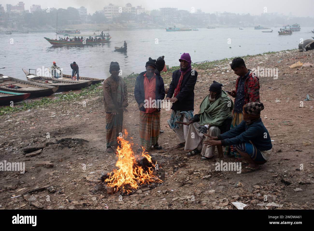 Dhaka, Bangladesh. 22nd Jan, 2024. Workers surround a bon-fire for ...