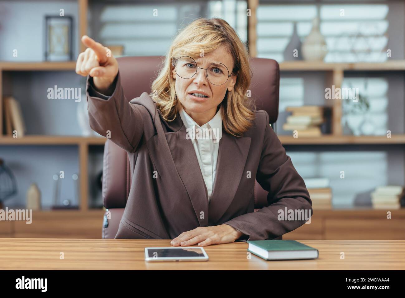 Mature businesswoman in glasses points authoritatively in a well ...