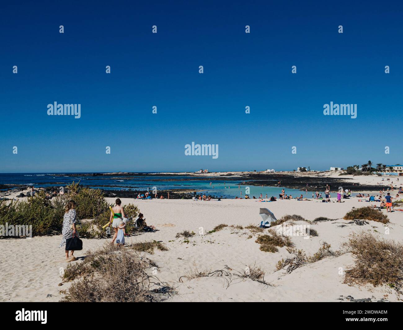 People sunbathing and bathing in the blue waters by El Cotillo beach ...