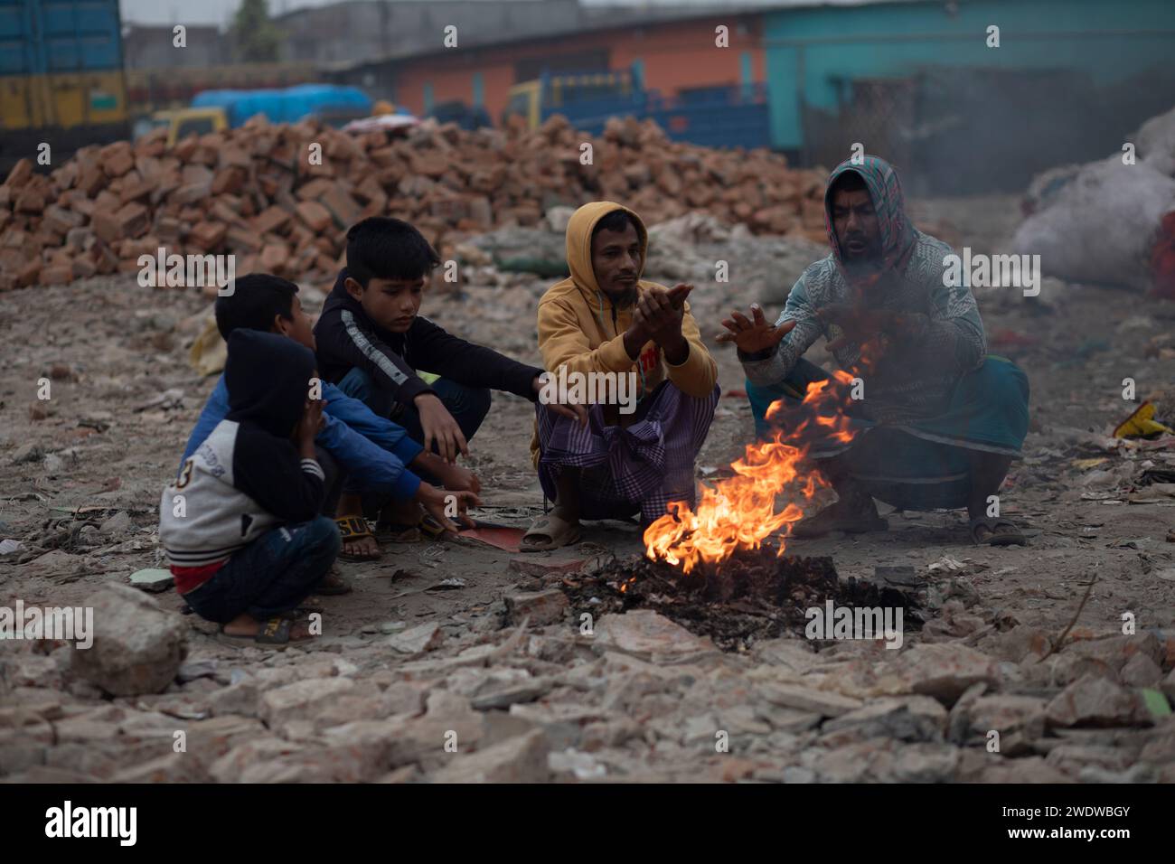 Dhaka, Bangladesh. 22nd Jan, 2024. People warm themselves around a bon ...