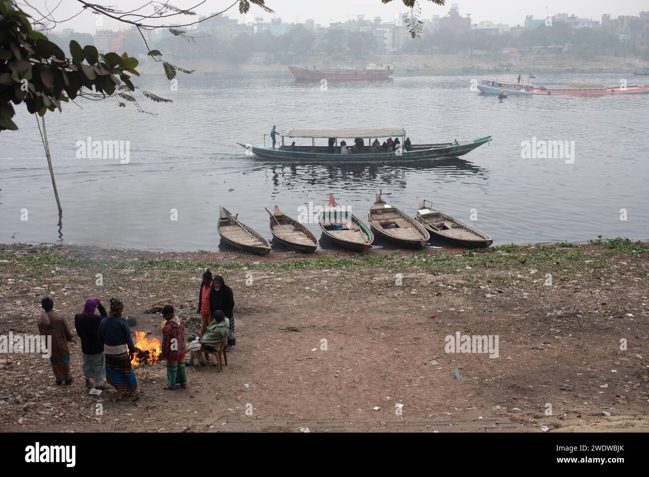 Dhaka, Bangladesh. 22nd Jan, 2024. Workers surround a bon-fire for ...