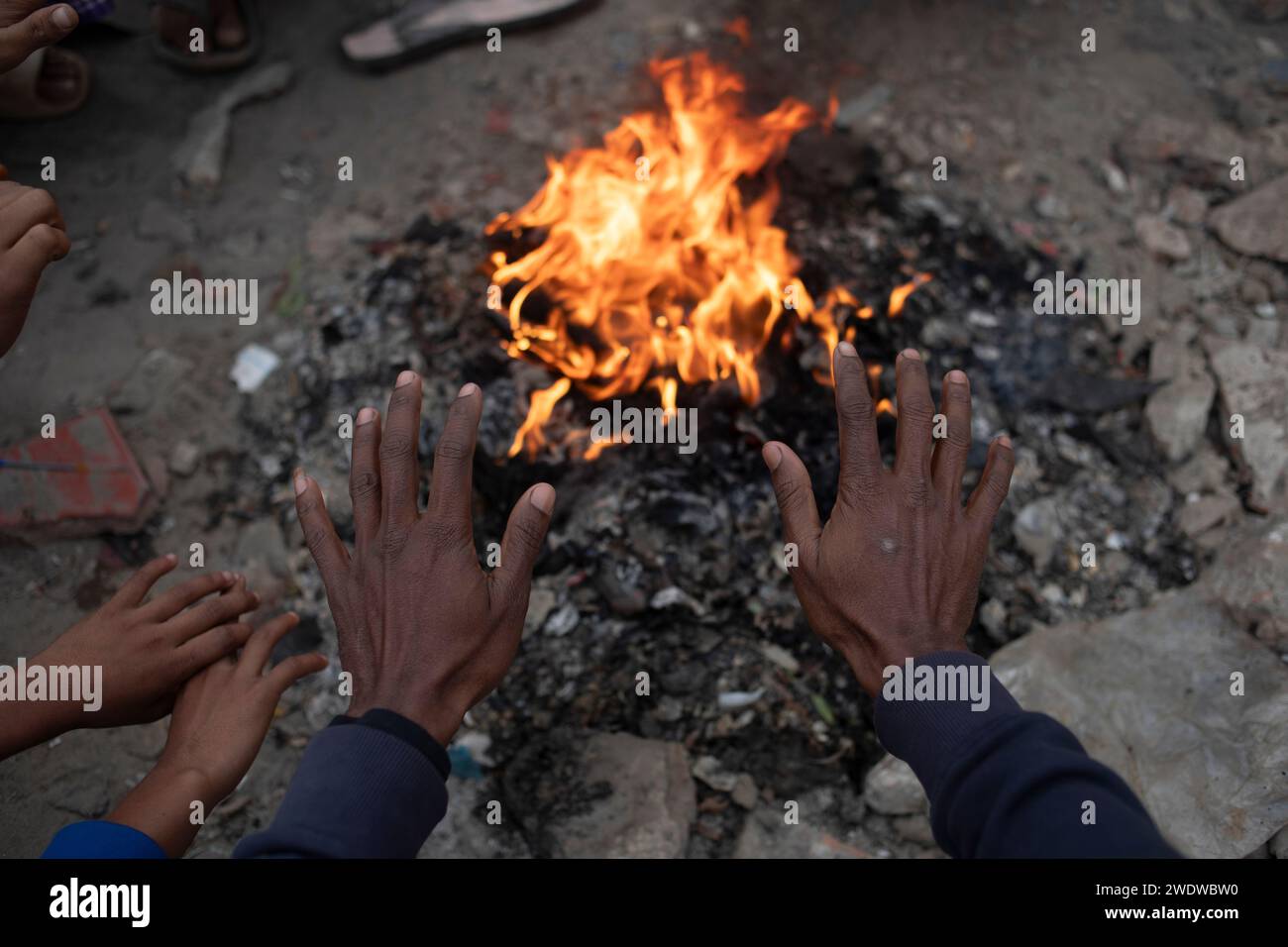 Dhaka, Bangladesh. 22nd Jan, 2024. People warm themselves around a bon ...