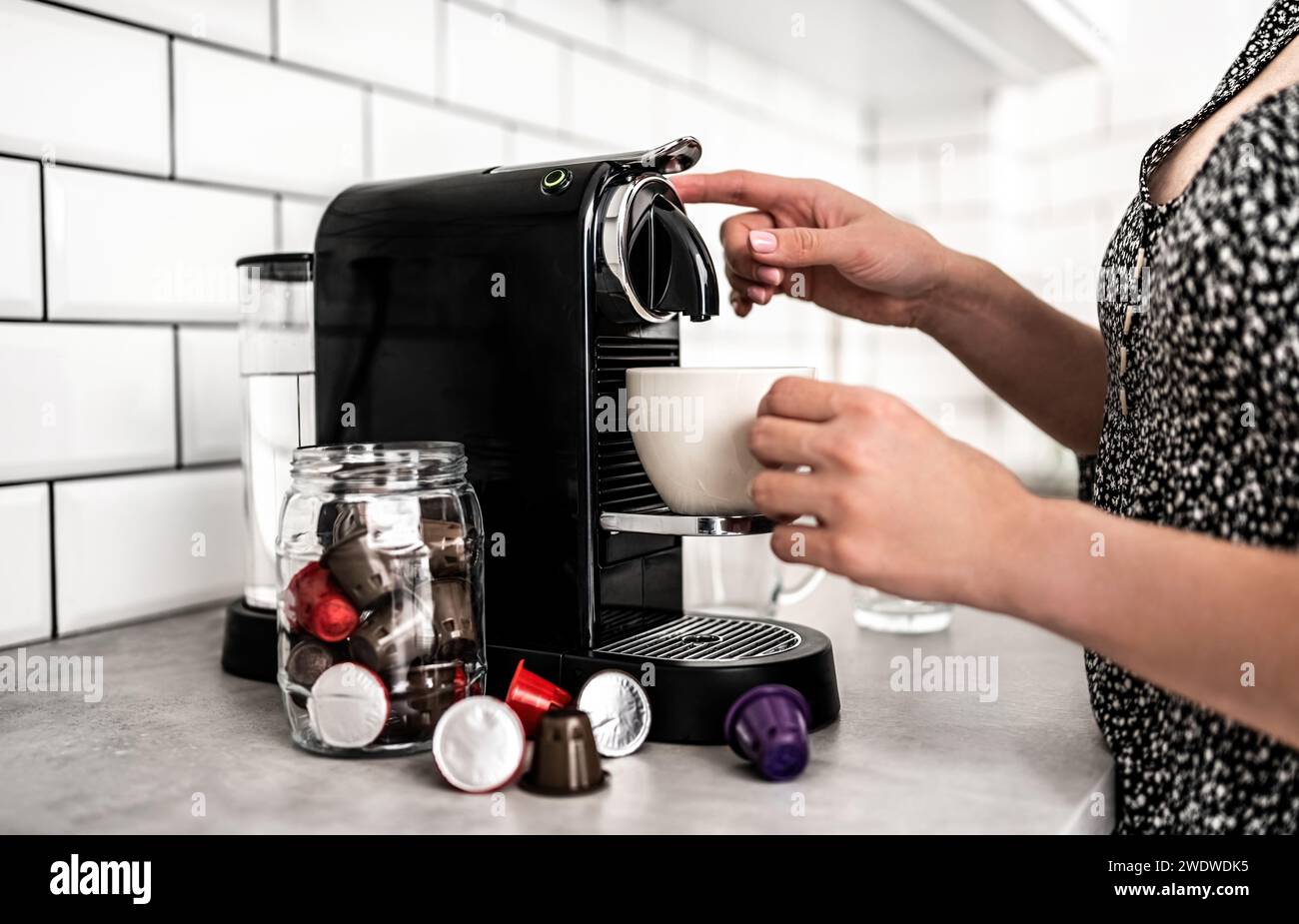 Girl with capsule coffee machine and cup at kitchen. Woman preparing ...