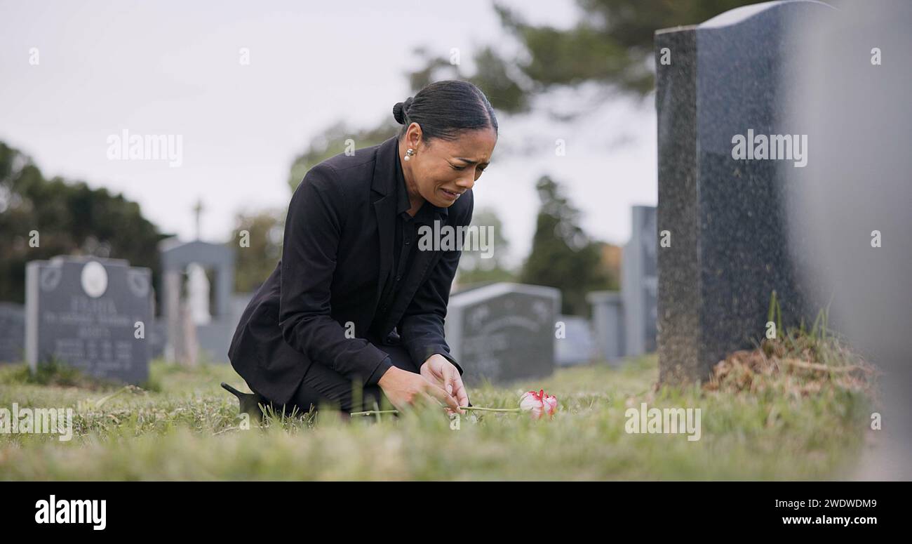 Sad woman, graveyard and crying with rose by tombstone in mourning ...