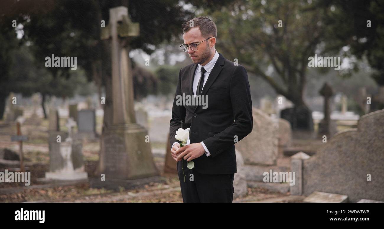 Funeral, cemetery and man with flower by tombstone for remembrance ...