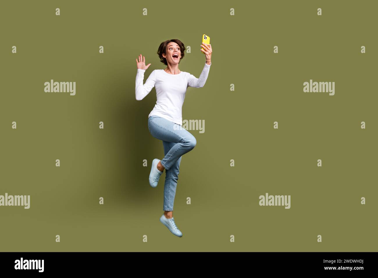 Full size photo of attractive young woman jumping video call palm wave ...