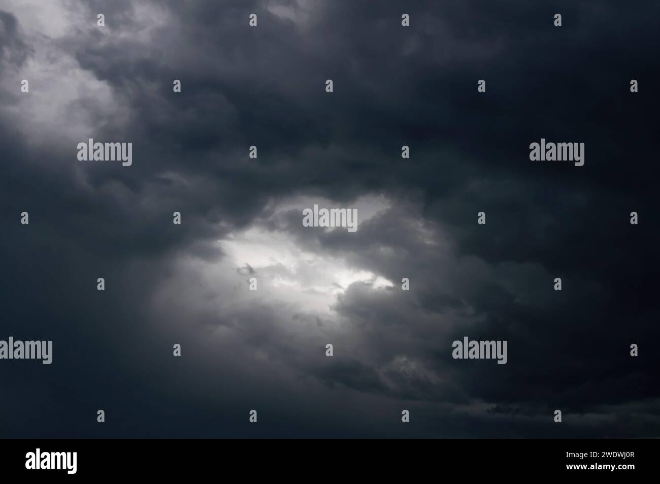 Gray clouds before thunderstorm. Gleam of light in black clouds before ...