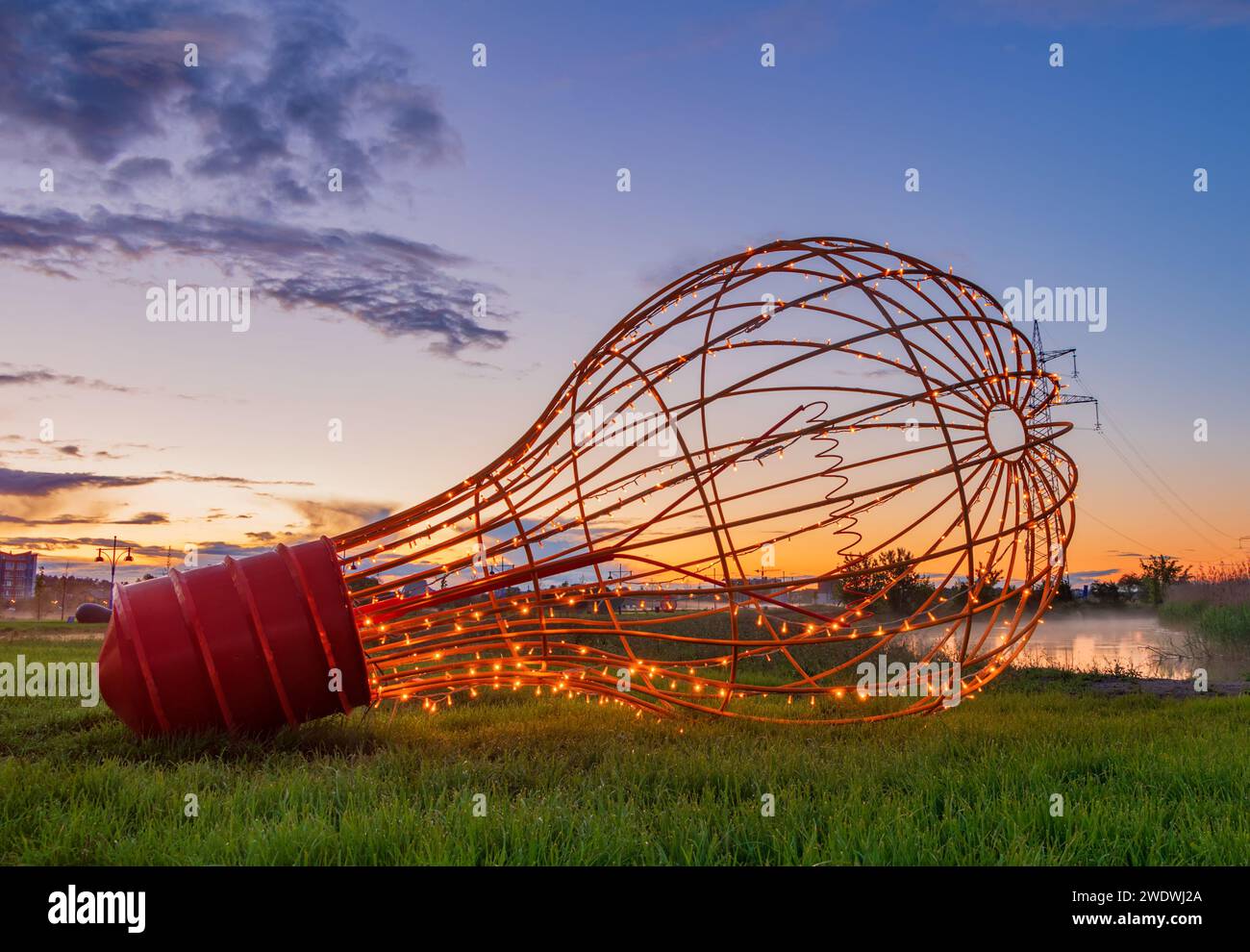Decorative metal lamp with luminous bulbs in a city park by foggy river ...