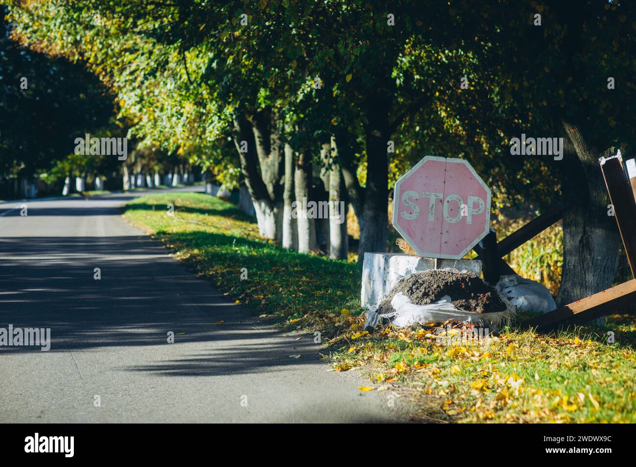 stop sign near the road and anti-tank hedgehogs war Stock Photo - Alamy