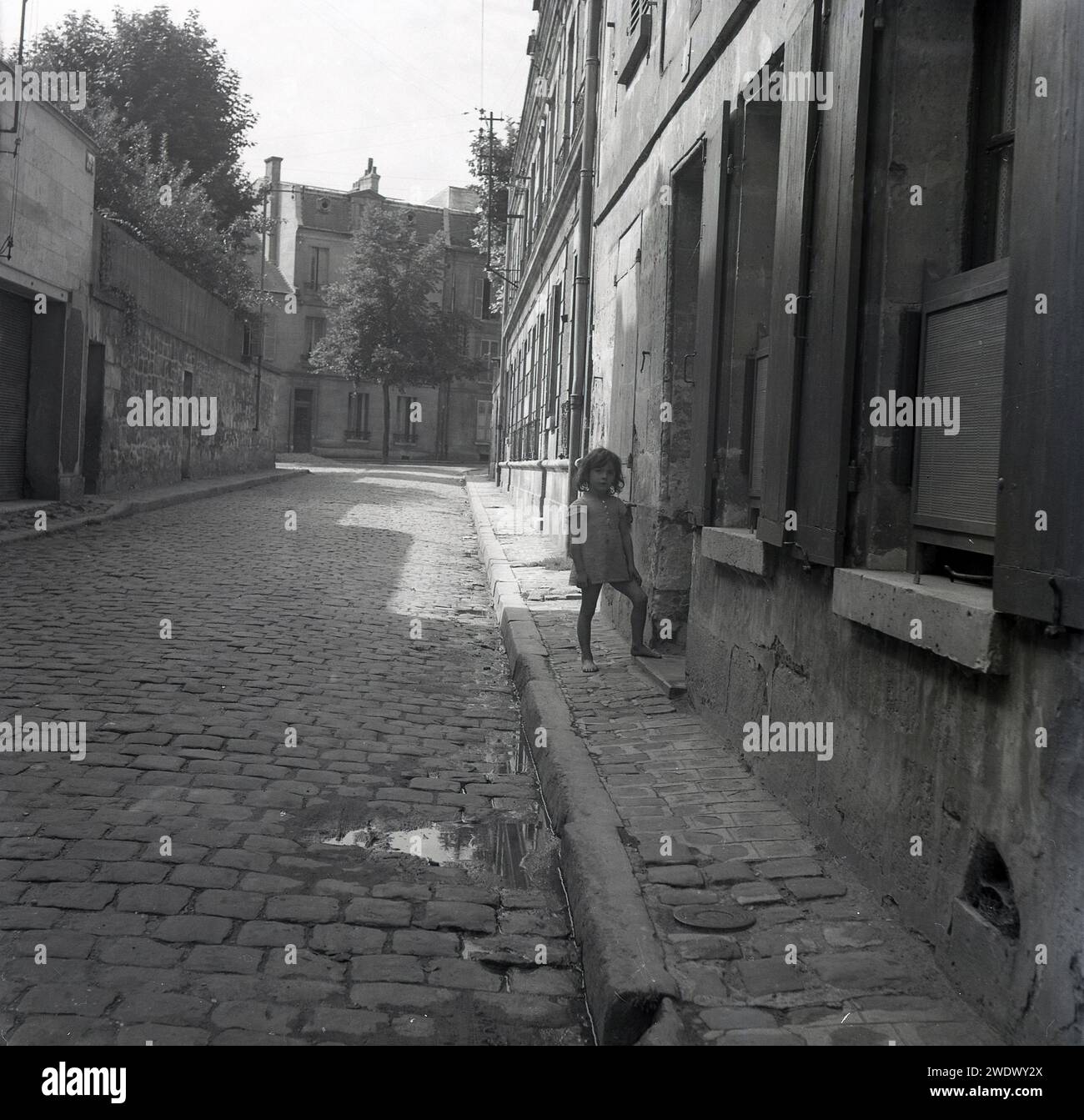 1950s, historical, outside in a cobbled street, on a cobbled pavement ...