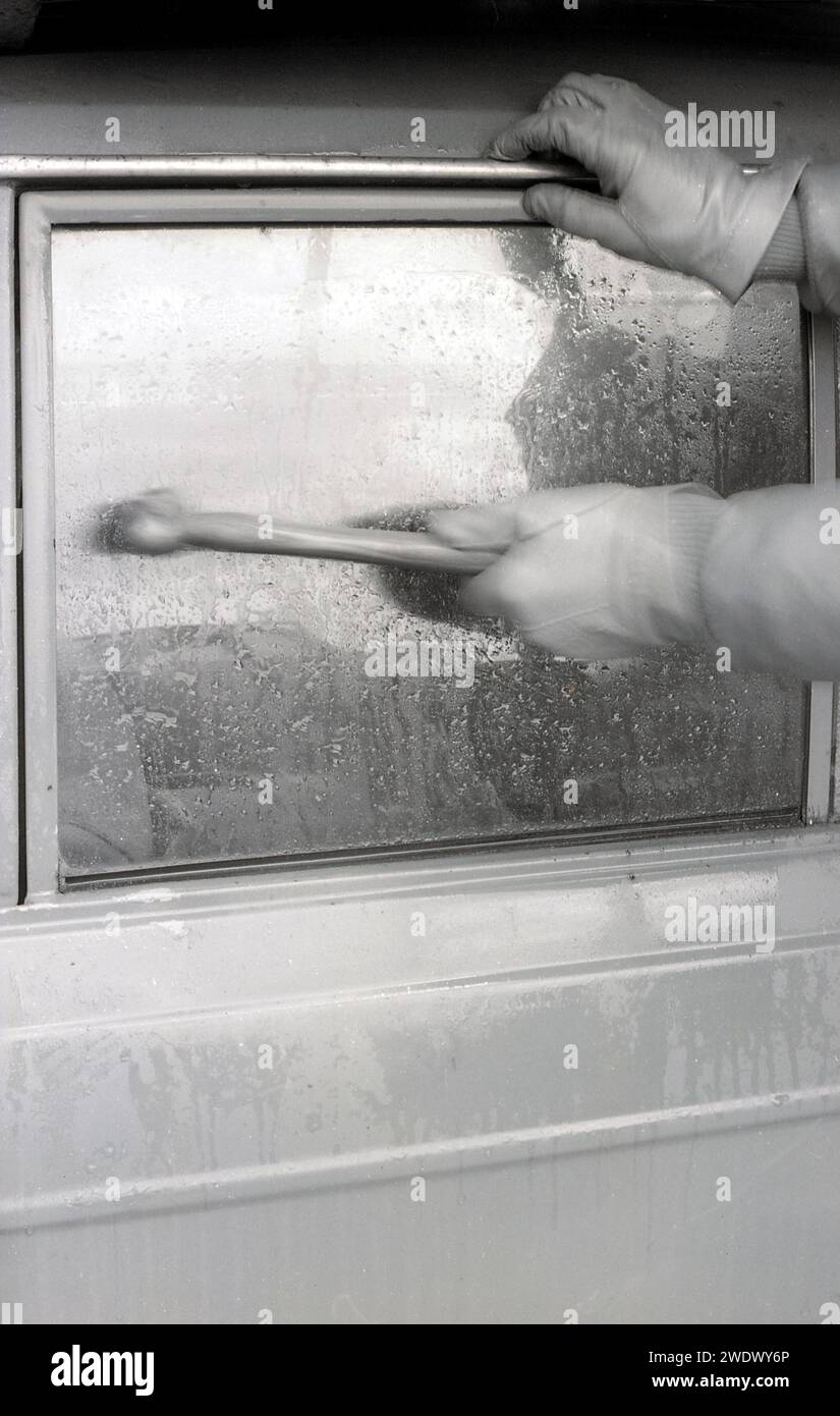 1970s, historical, a gloved hand thief attempting to smash a car window ...