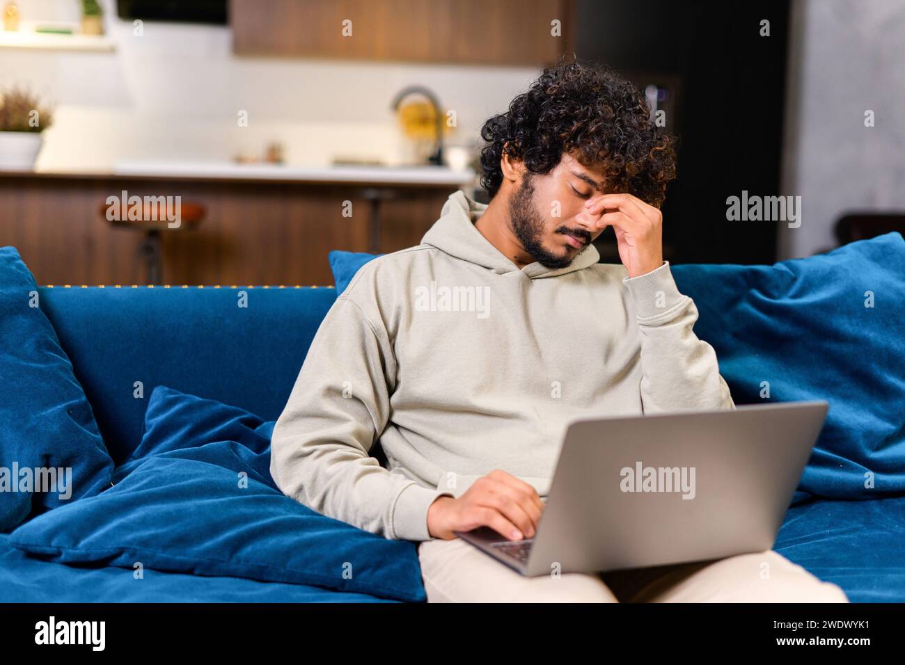 Indian young man is frustrated, rubbing his forehead while looking at ...