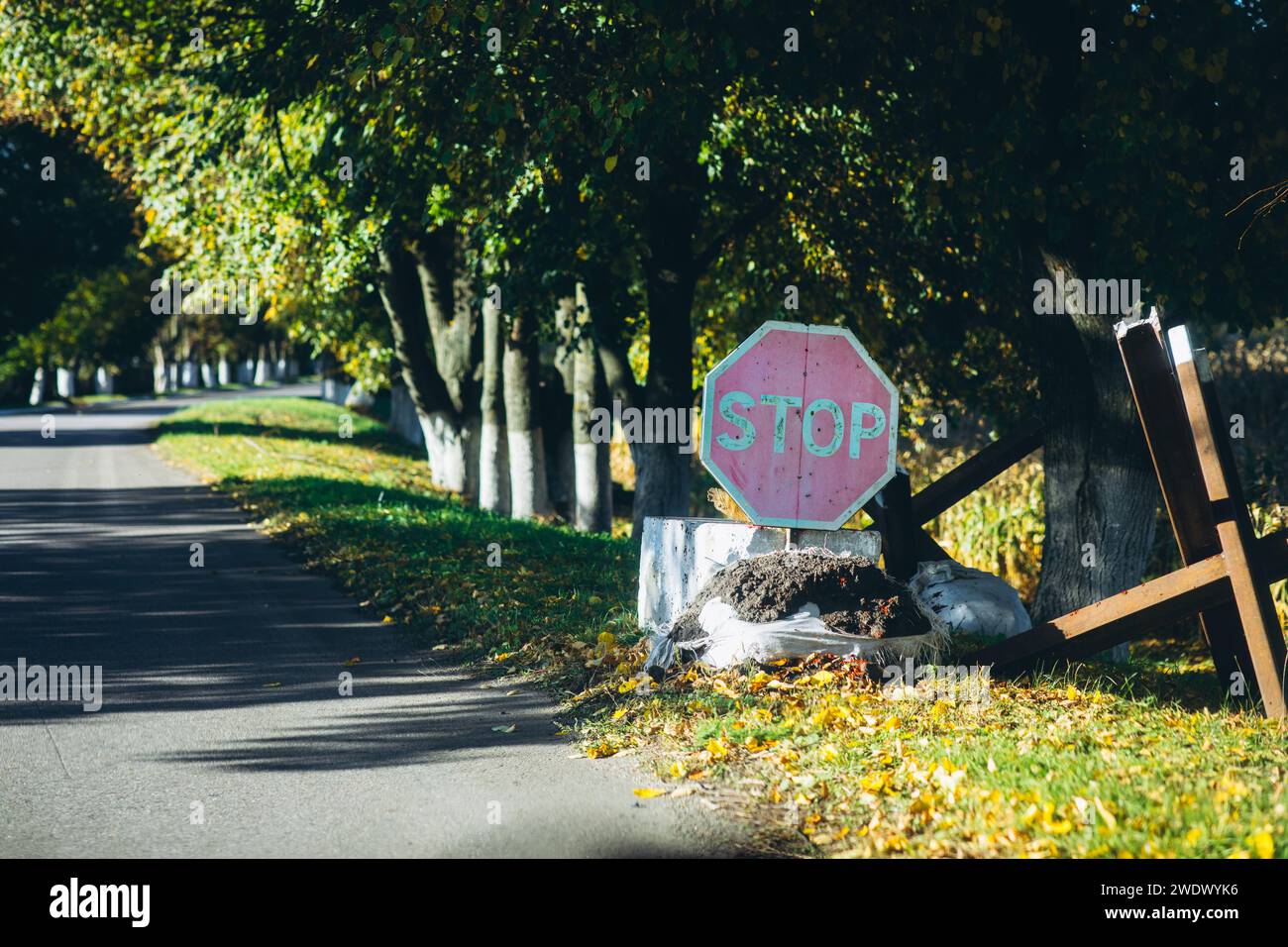 stop sign near the road and anti-tank hedgehogs war Stock Photo - Alamy