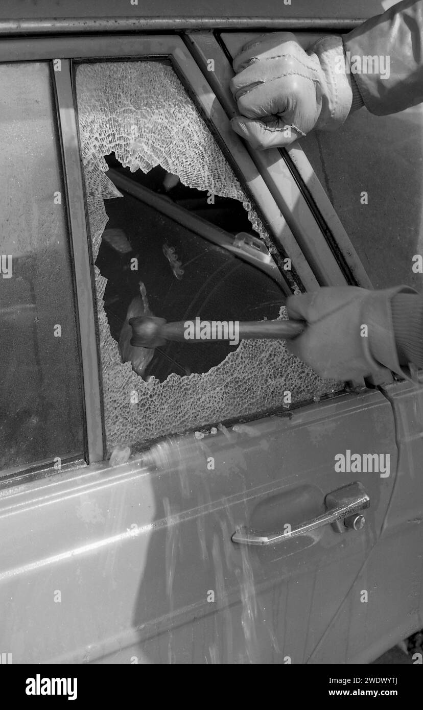 1970s, historical, a gloved hand car thief smashing a car window, a ...