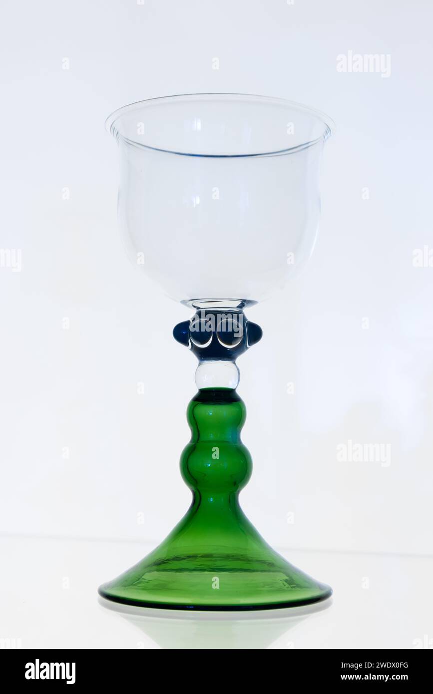 A glass goblet with green base is on white background, vertical studio ...