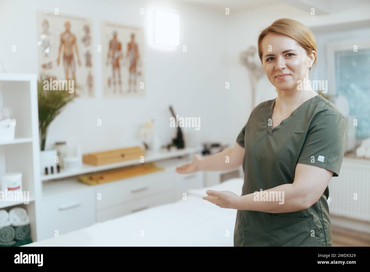 Healthcare time. happy female medical massage therapist in massage cabinet welcoming Stock Photo ...