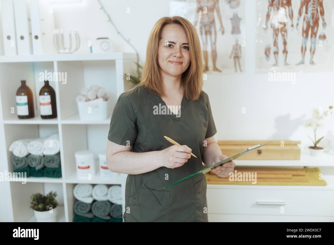 Healthcare time. happy female massage therapist in massage cabinet with clipboard Stock Photo ...