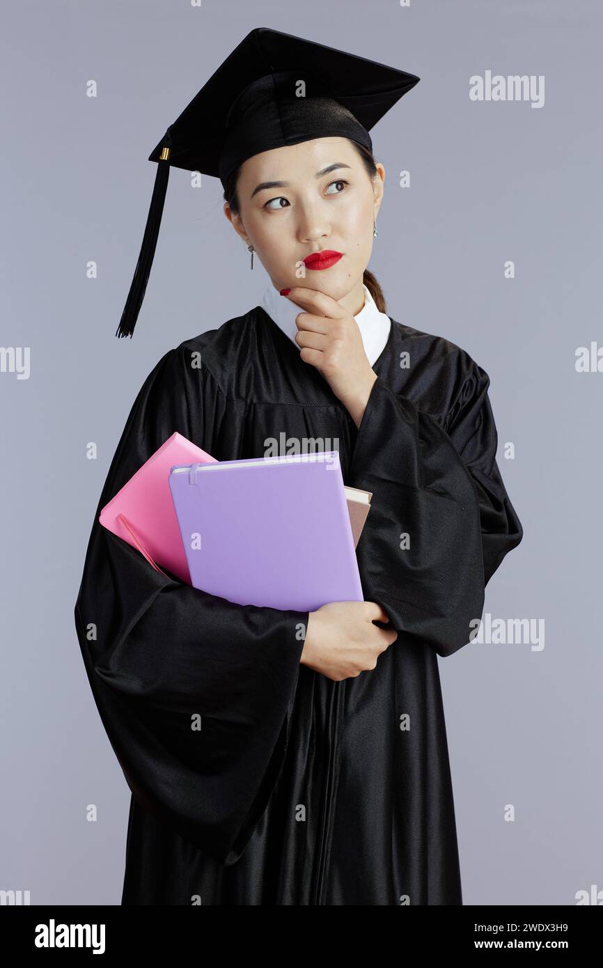 pensive young graduate student asian woman with books and notebooks ...