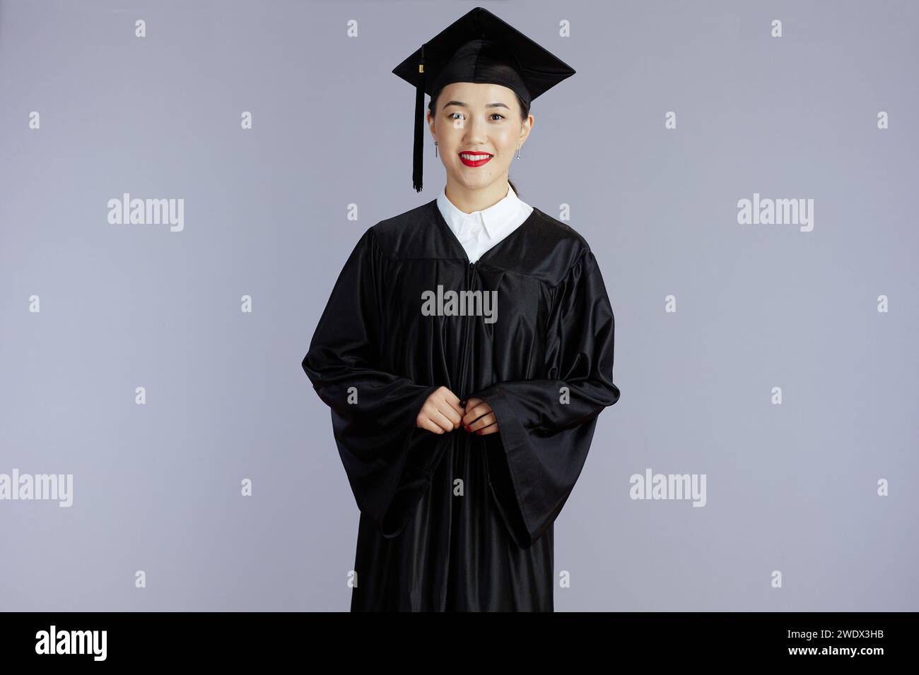 smiling modern female asian graduate student in graduation gown with ...