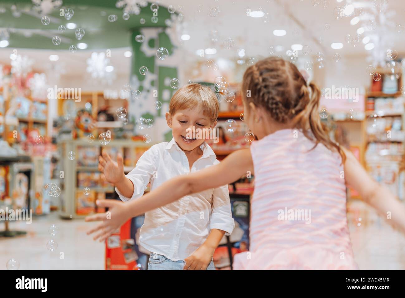 Happy Siblings Playing with Soap Bubbles Stock Photo - Alamy