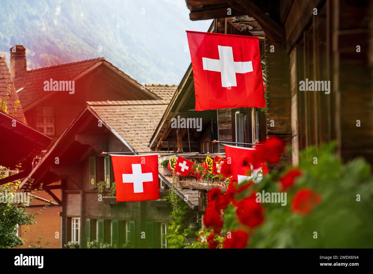 swiss flags with wooden houses in a swiss city Stock Photo - Alamy
