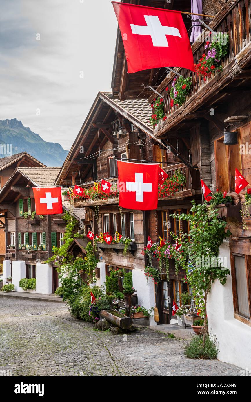 swiss flags with wooden houses in a swiss city Stock Photo - Alamy