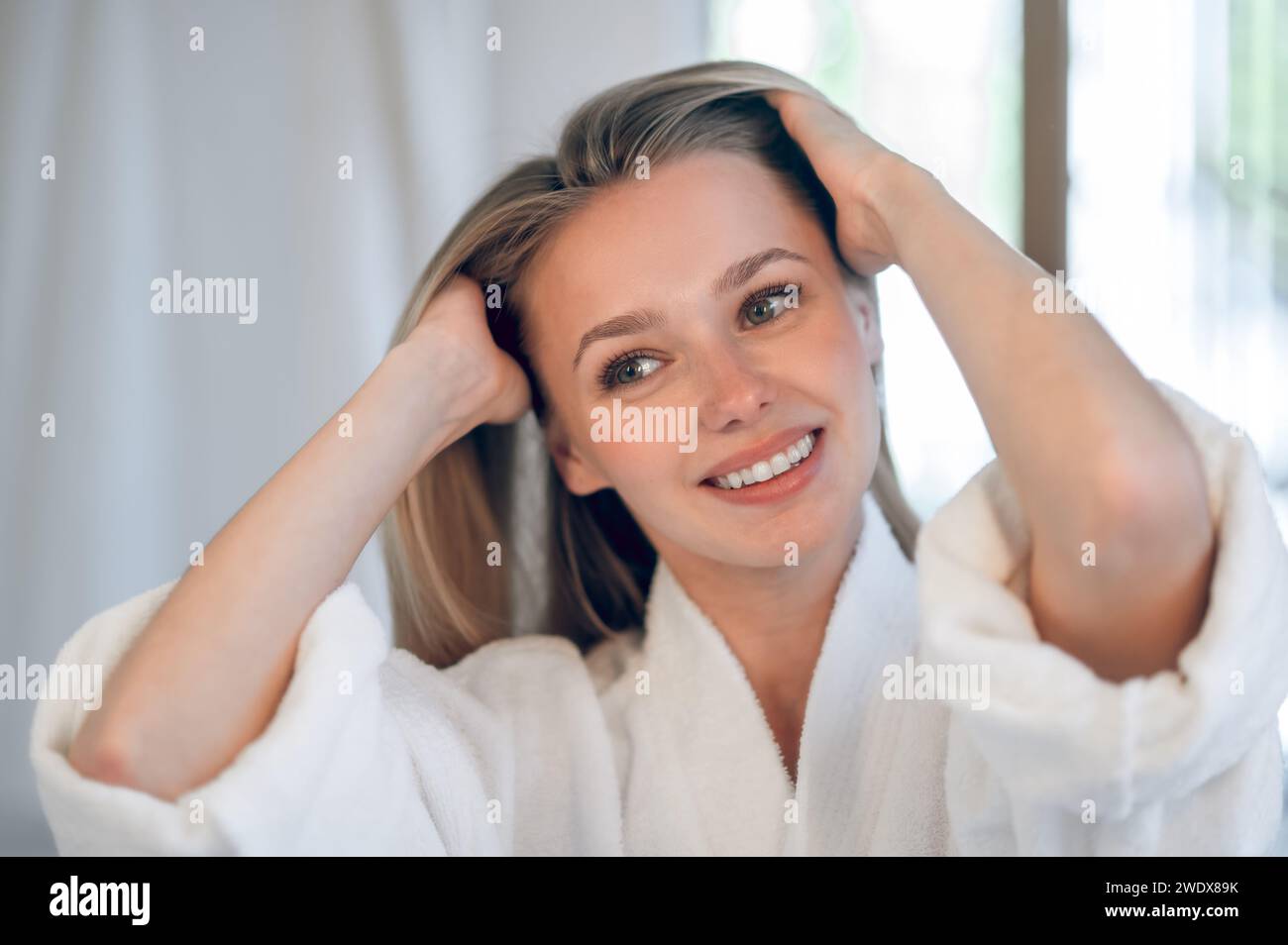 Blonde young woman making hair Stock Photo - Alamy