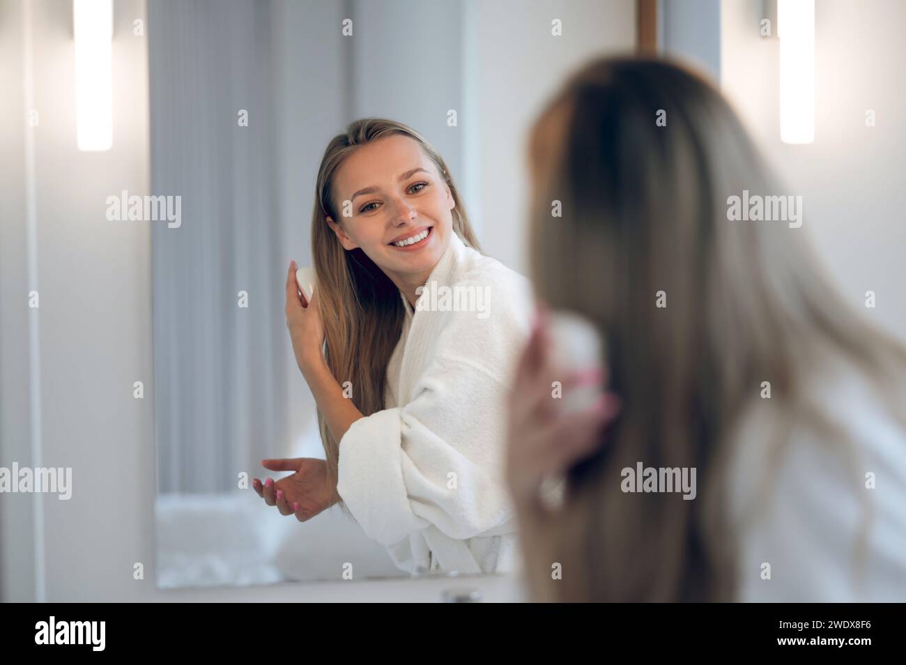 Long-haired pretty woman making hair at the mirror Stock Photo - Alamy