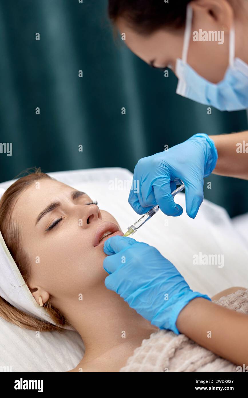 beautician makes injections to enlarge the lips of beautiful woman ...