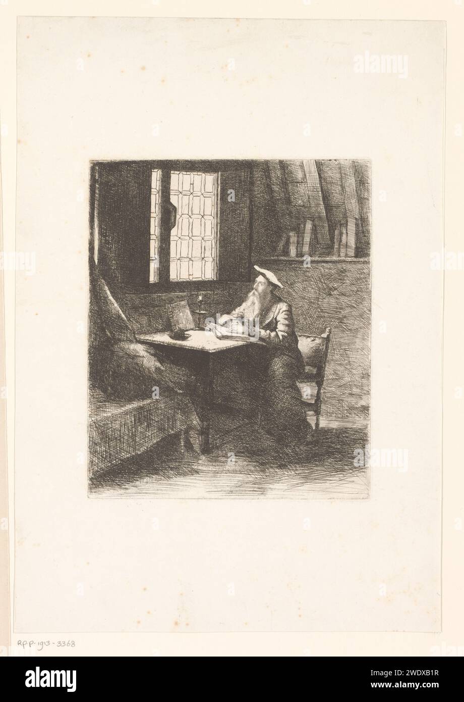 Man is sitting at the table with an open book and looks out through a ...