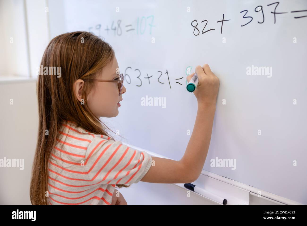 Pupil girl doing mathematics task on while board during lesson Stock ...