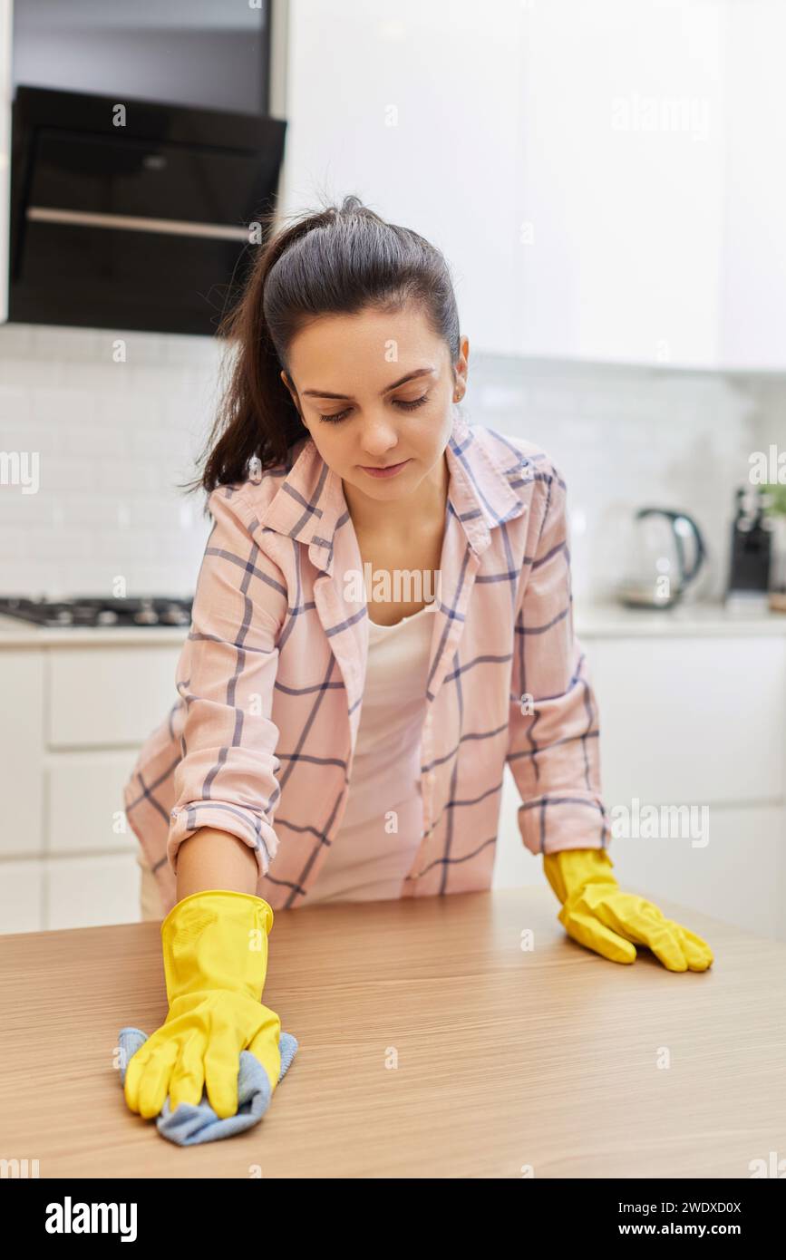 young woman wiping wooden table with microfiber cloth. chores at home ...