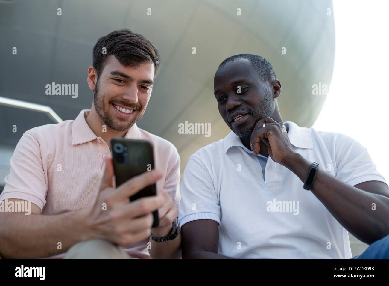 Two colleagues sitting together on steps and talking Stock Photo - Alamy
