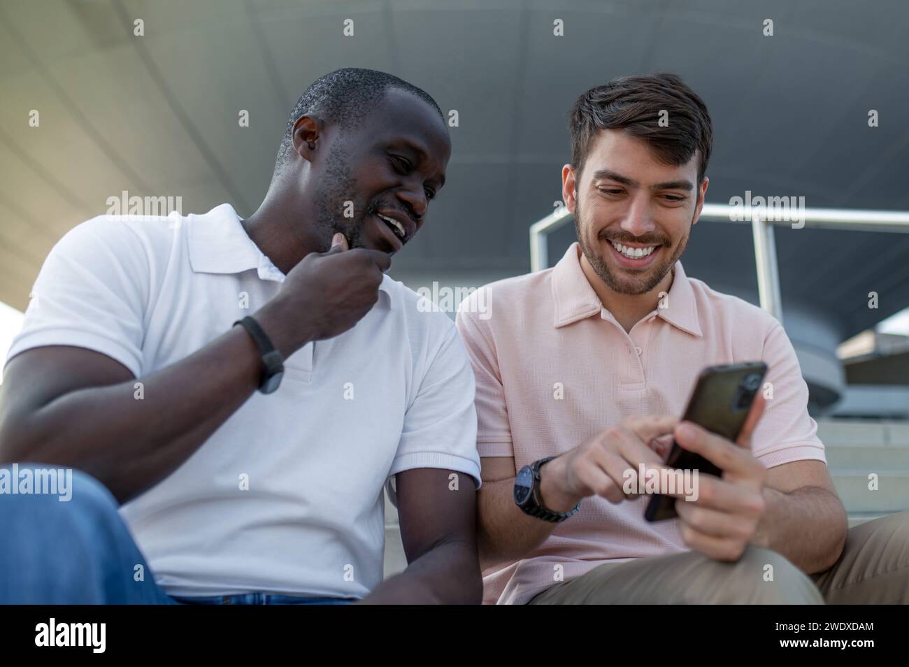 Two colleagues sitting together on steps and talking Stock Photo - Alamy