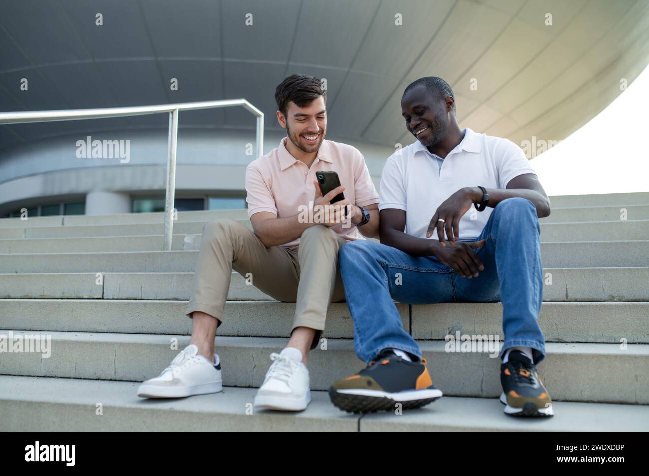 Two friends watching something on the phone and smiling Stock Photo - Alamy