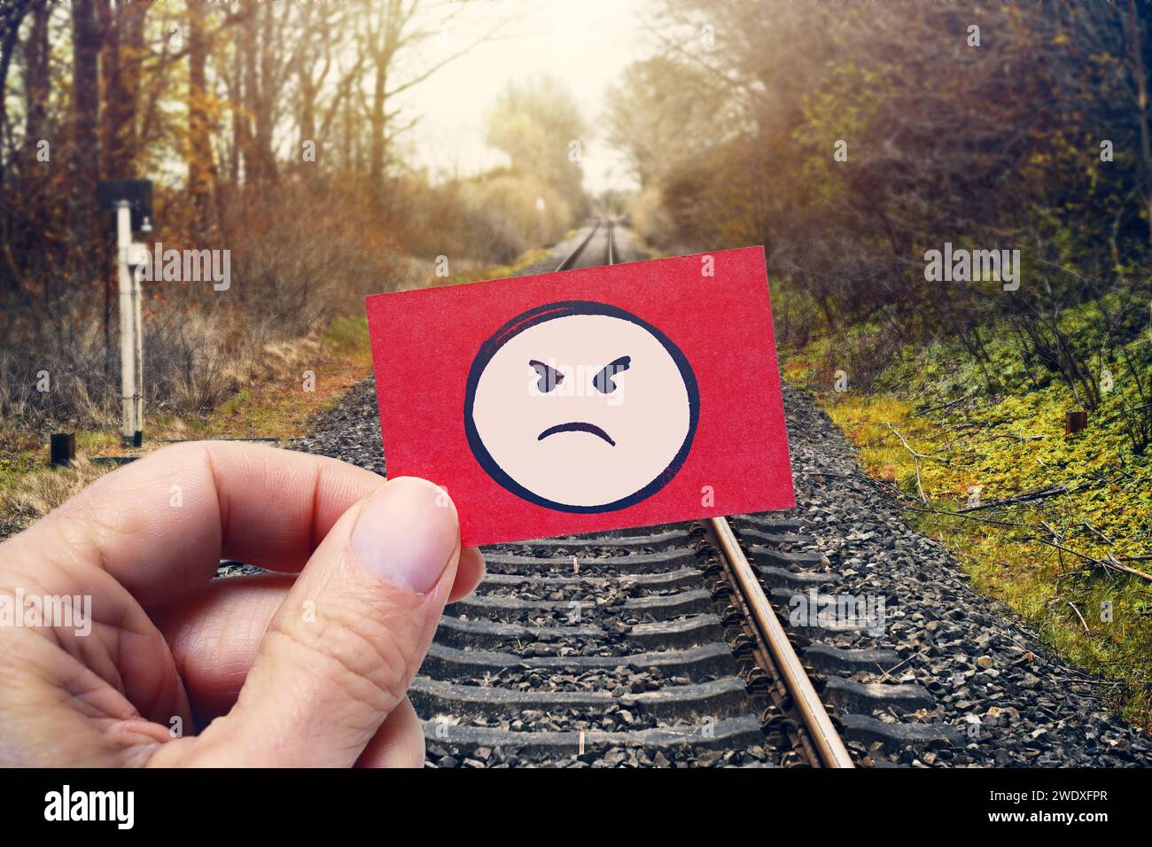 FOTOMONTAGE, Hand hält Zettel mit wütendem Emoji vor leeren ...