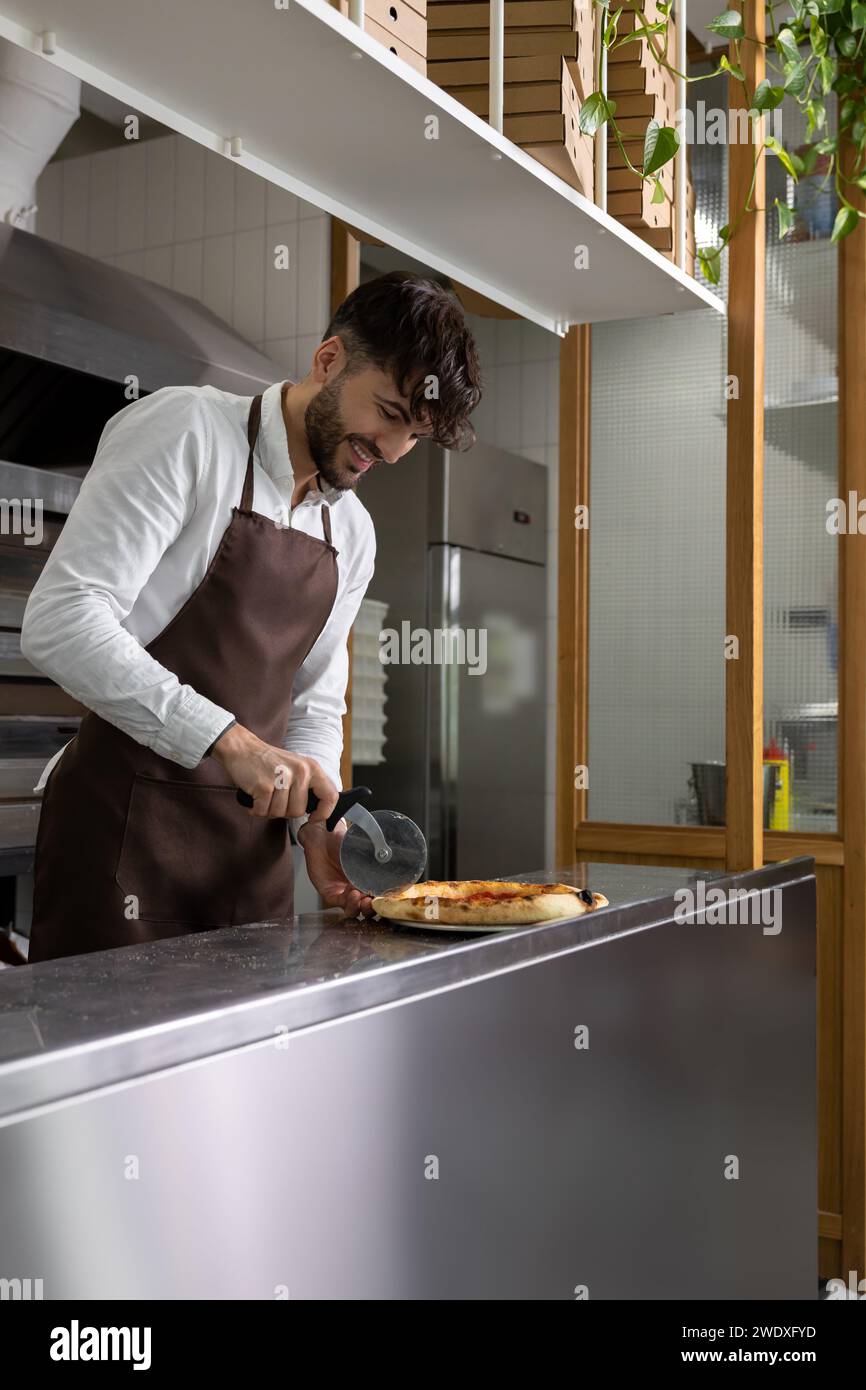 Dark-haired young man cooking pizza in pizzeria Stock Photo - Alamy