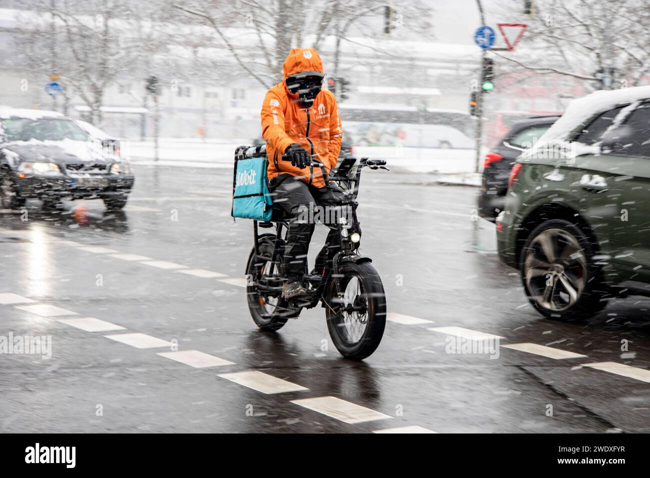 Ein Volt Fahrer mit Lieferando Jakett auf dem Fahrrad unterm Schneefall ...