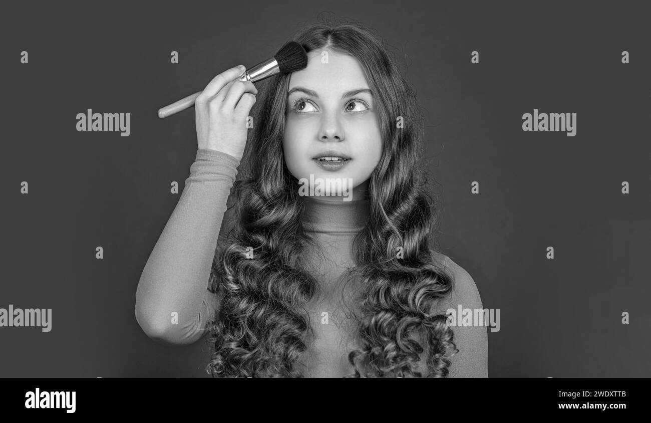 child with curly hair apply powder on face with makeup brush Stock ...
