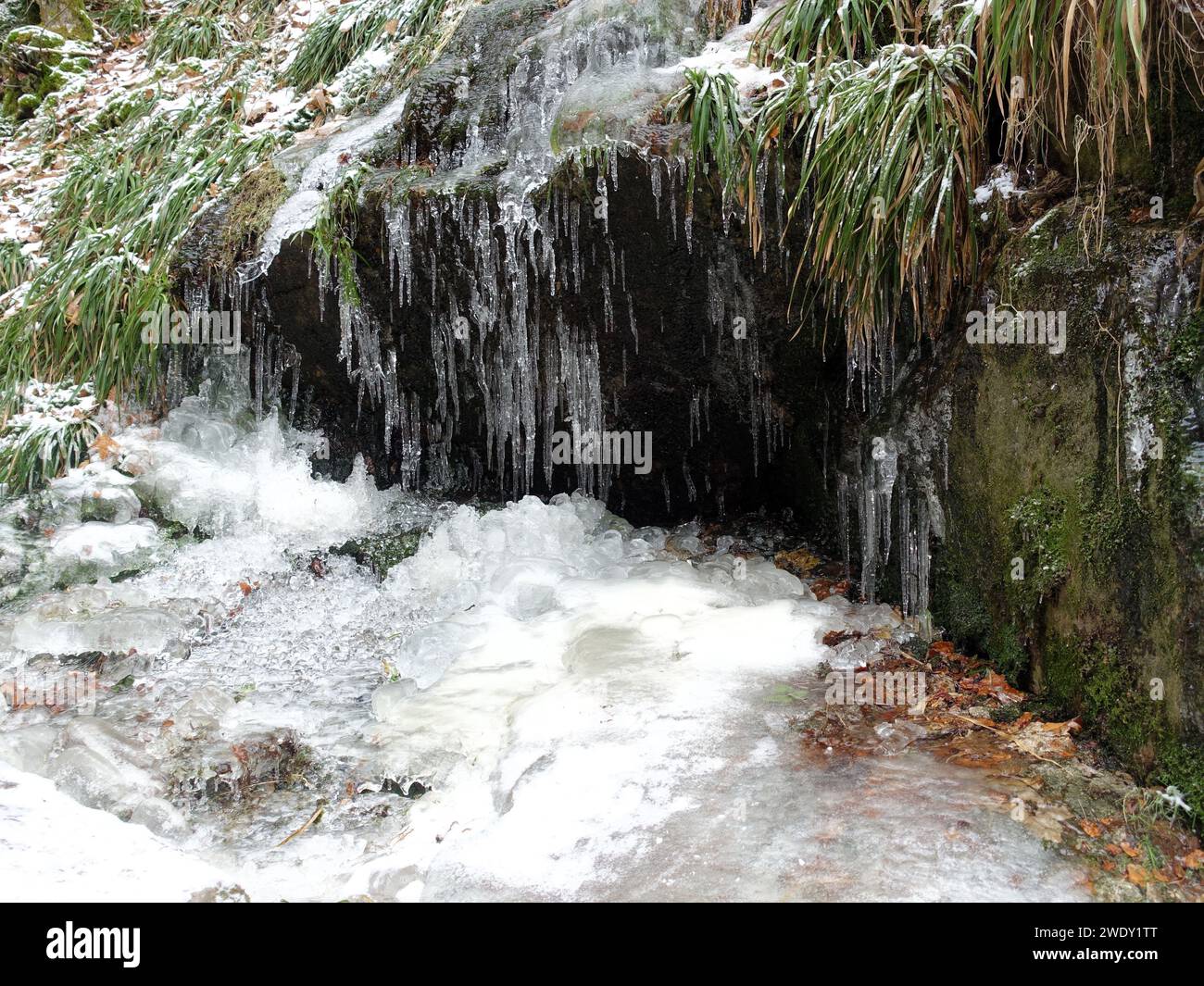 Waterfall with snowy top cascades into water Stock Photo - Alamy