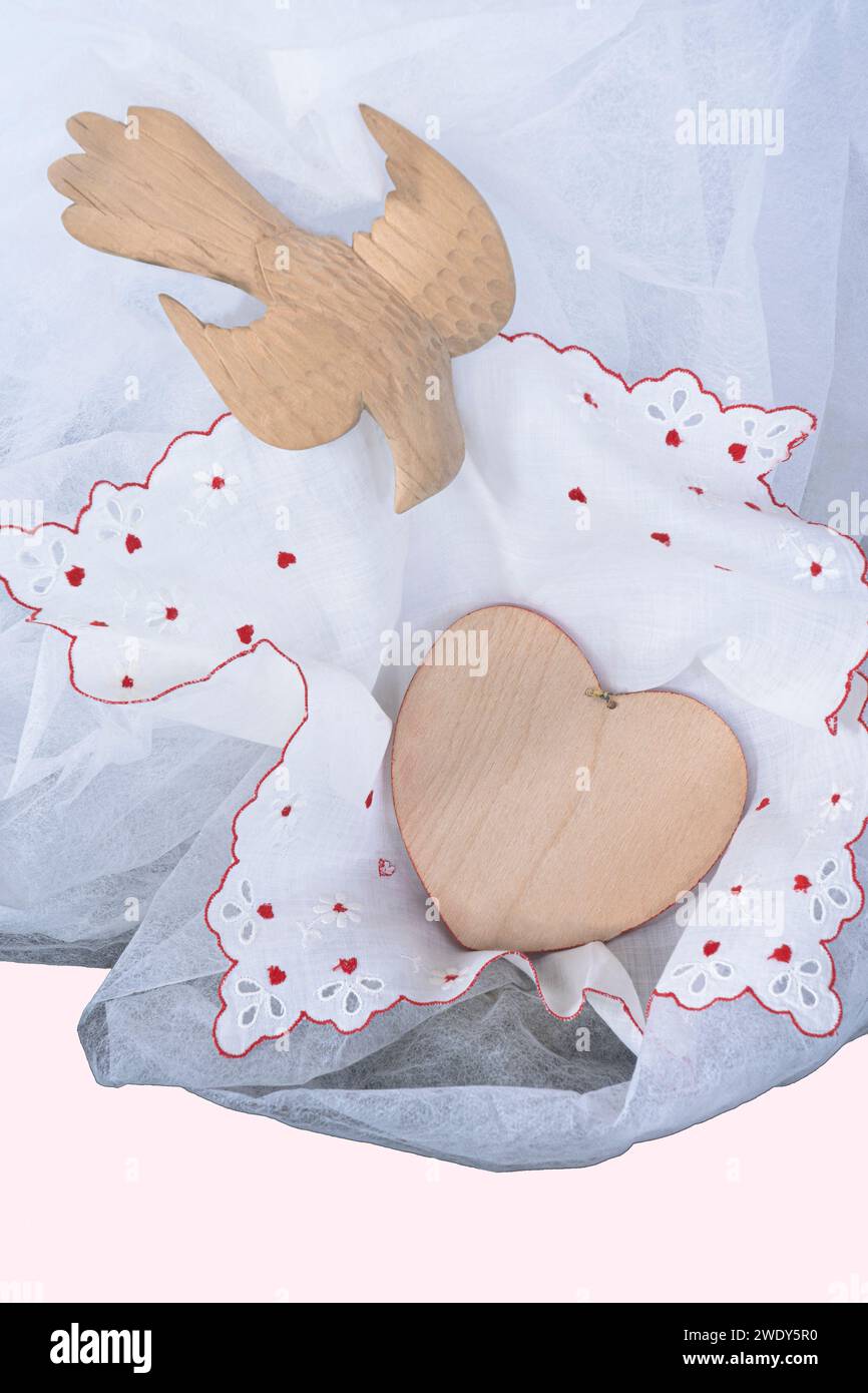 Wood dove is descending from clouds with carved heart below. Red heart ...
