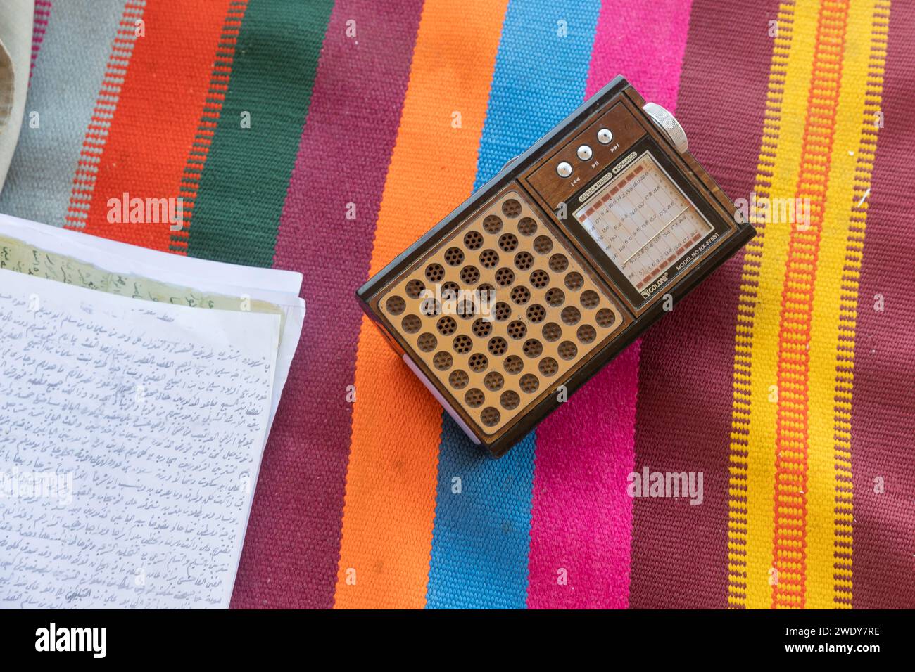 A radio receiver and a sheet with Arabic letters on the fabric texture ...