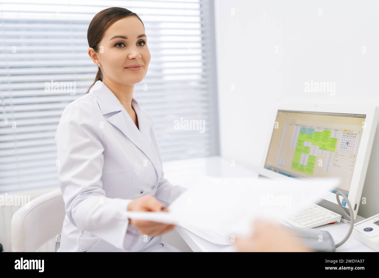 Smiling female doctor giving prescription paper to unrecognizable ...