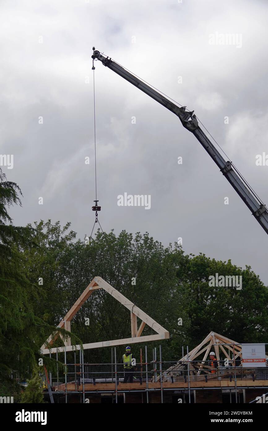 Roof trusses being installed by crane on a construction site of a ...