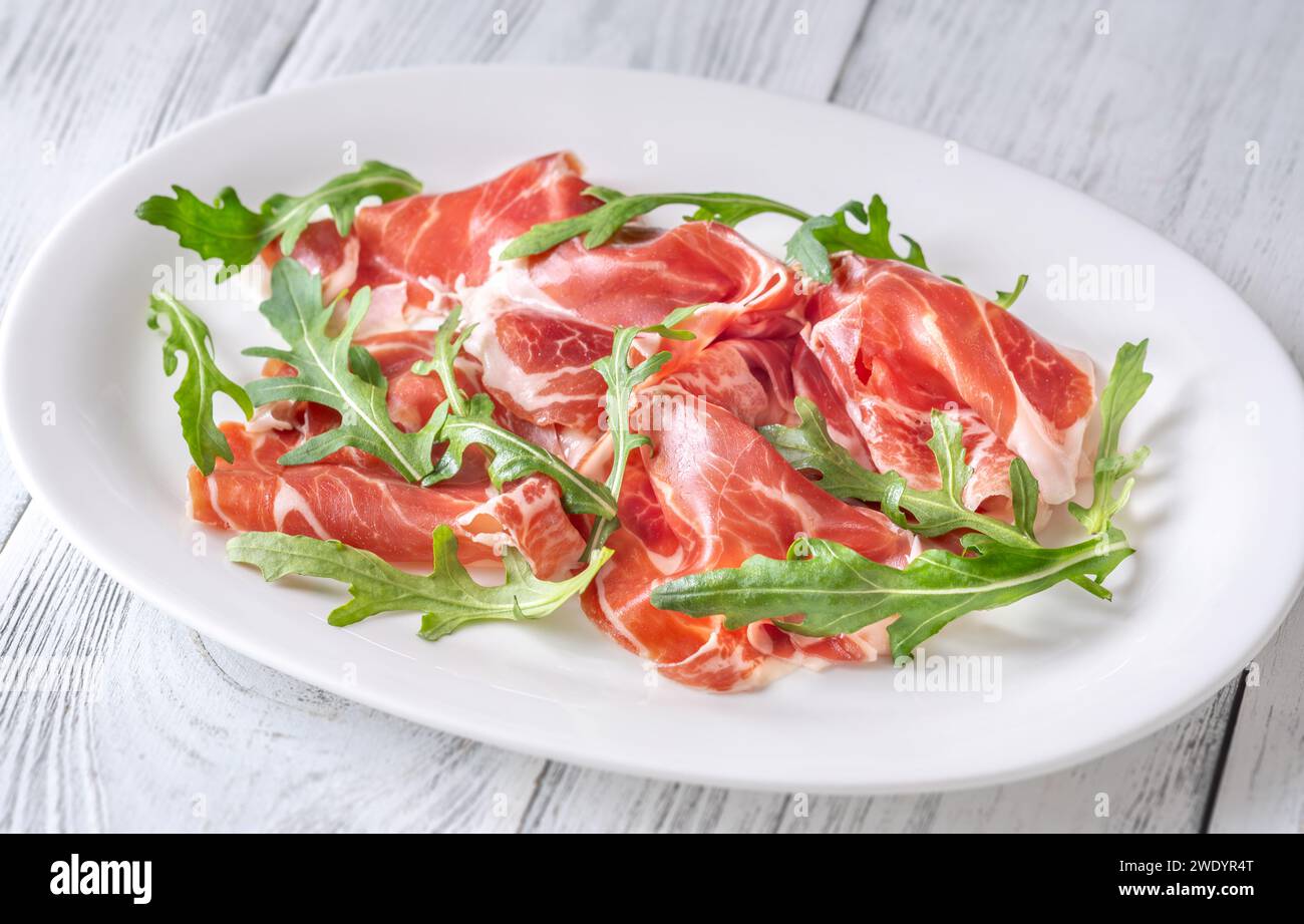 Portion of Prosciutto crudo ham with arugula Stock Photo - Alamy