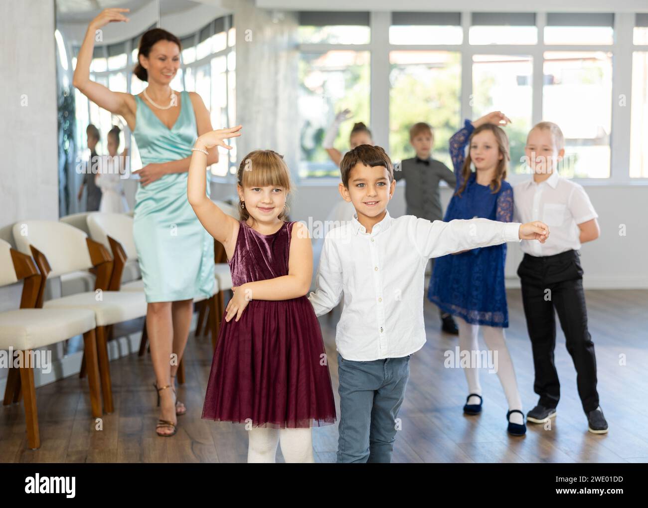 Little children in elegant dresses practicing waltz dance in school ...
