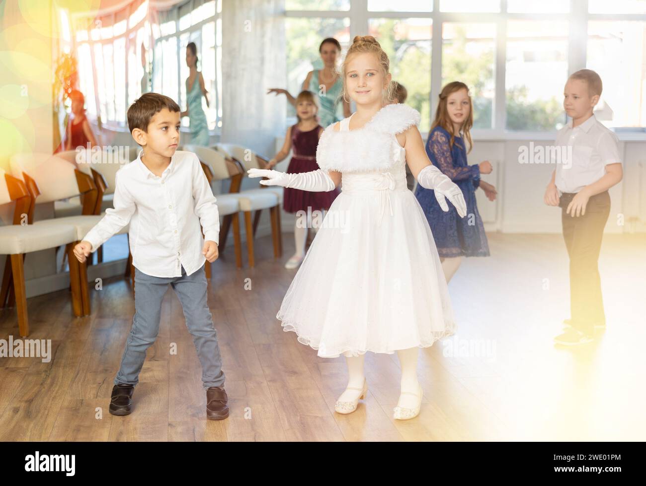 Little children in elegant dresses practicing twist dance in school ...